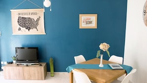 Uma sala de estar moderna com parede azul, um suporte de TV de madeira, uma mesa de jantar com cadeiras e um mapa dos EUA pendurado.
