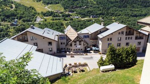Um edifício de vários andares com um pátio central, rodeado por vegetação exuberante e uma paisagem montanhosa.