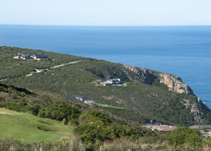 Paisagem costeira com um campo de golfe, um penhasco e vários edifícios.