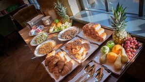 Um buffet de café da manhã com diversos pastéis, frutas e acompanhamentos.