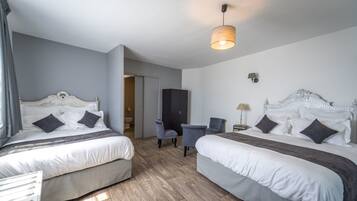 Quarto de hotel com duas camas, uma escrivaninha, uma cadeira e um guarda-roupa.