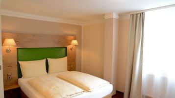 Uma cama de casal com cabeceira verde, duas luminárias de cabeceira e uma janela com cortinas.