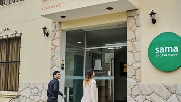 Um edifício com uma placa indicando 'CASA ANDINA STANDARD' e uma placa verde para 'sama by CASA ANDINA'.
