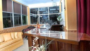 Uma área de recepção com uma mesa de vidro, um sofá e uma janela grande com vista para o exterior.