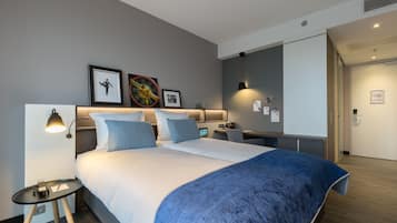 Quarto de hotel moderno com uma cama grande, mesas de cabeceira, uma escrivaninha e um guarda-roupa.