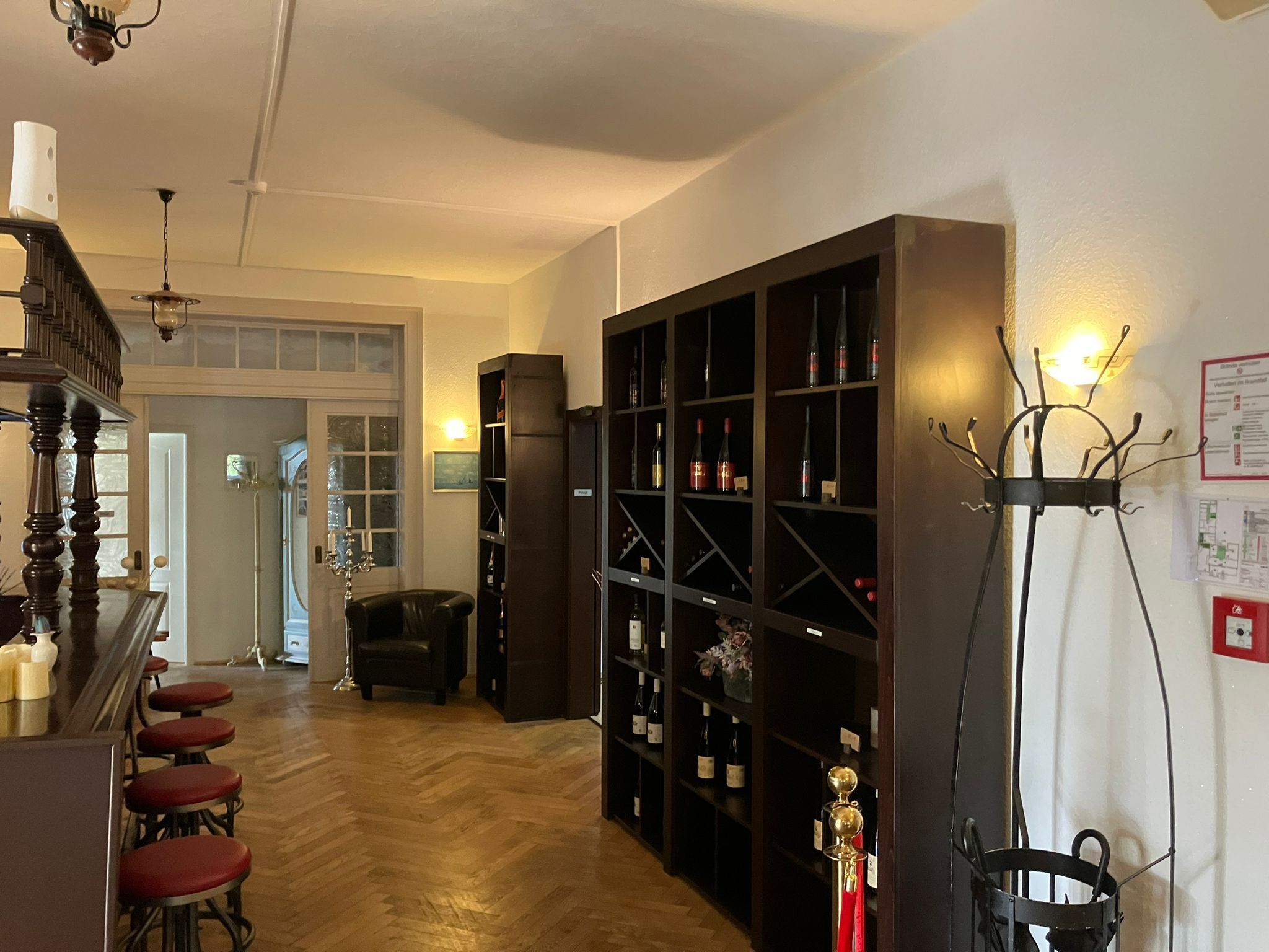 Uma área de bar com banquetas, uma adega e um candelabro.