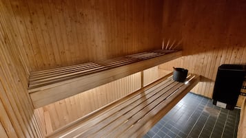 Uma sauna de madeira com bancos e um recipiente preto.