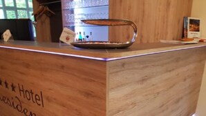 Bancada de recepção de hotel com acabamento em madeira e faixa de luz neon.