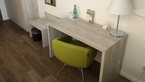 Quarto moderno com escrivaninha de madeira, cadeira verde, televisão e luminária.