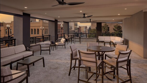 Terraço no telhado com área de estar ao ar livre, incluindo sofás, cadeiras e uma mesa redonda.
