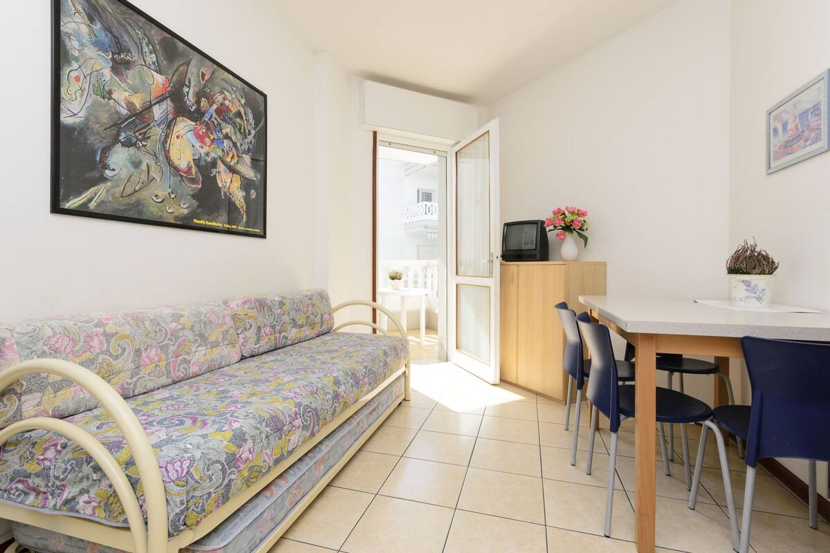 Um quarto acolhedor com sofá, mesa de jantar e cadeiras, televisão e um quadro na parede.