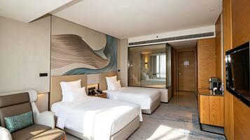 Quarto de hotel com duas camas, área de estar, televisão e um espelho grande.