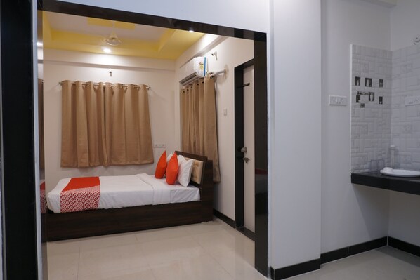 Quarto com cama, cortinas e banheiro com pia e espelho.