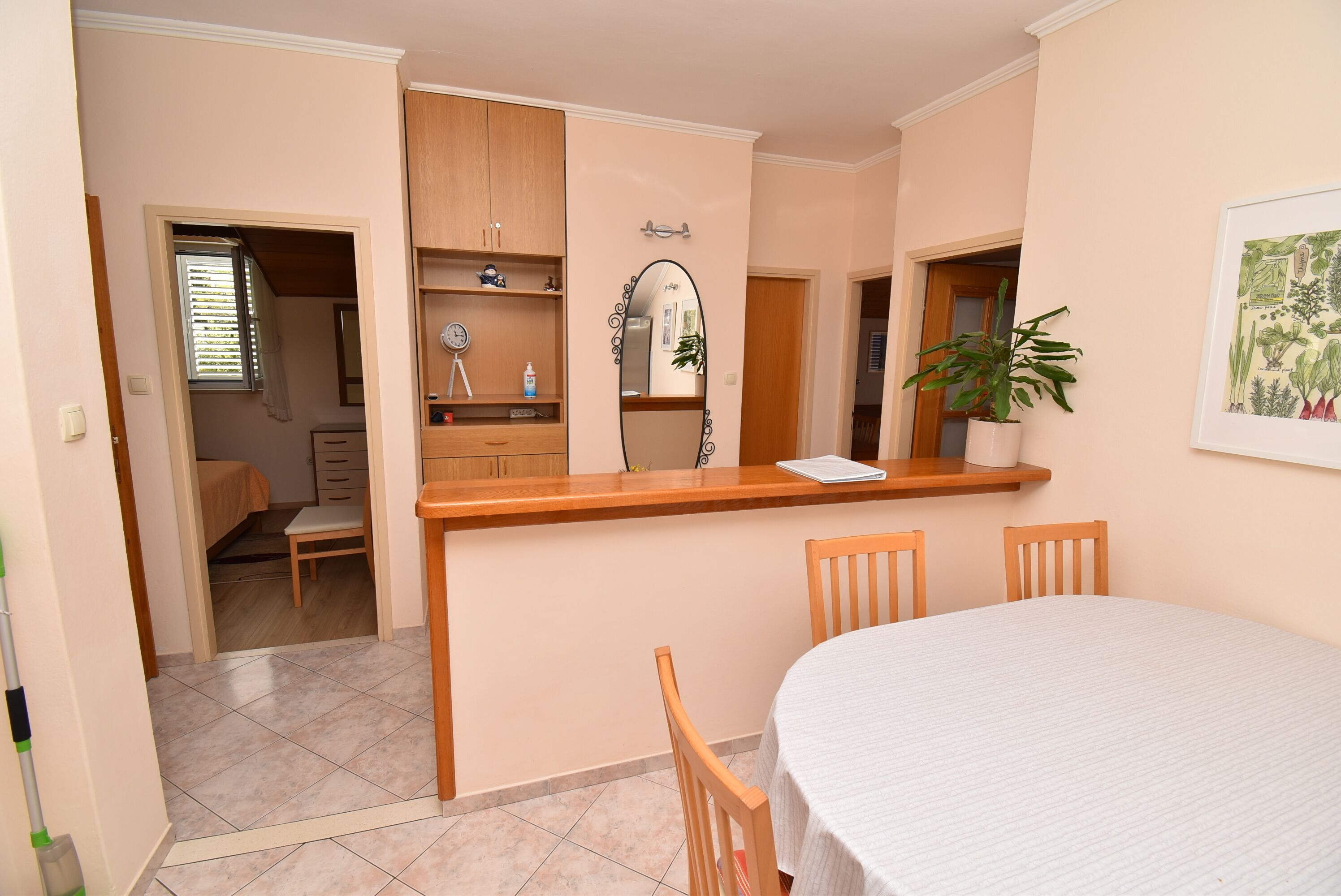 Uma cozinha compacta com armários de madeira, bancada e área de refeições com mesa e cadeiras.