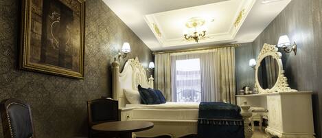 Um quarto com cama, cadeira, mesa, cômoda e espelho.