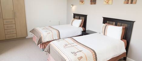 Quarto com duas camas de solteiro, um guarda-roupa e obras de arte na parede.