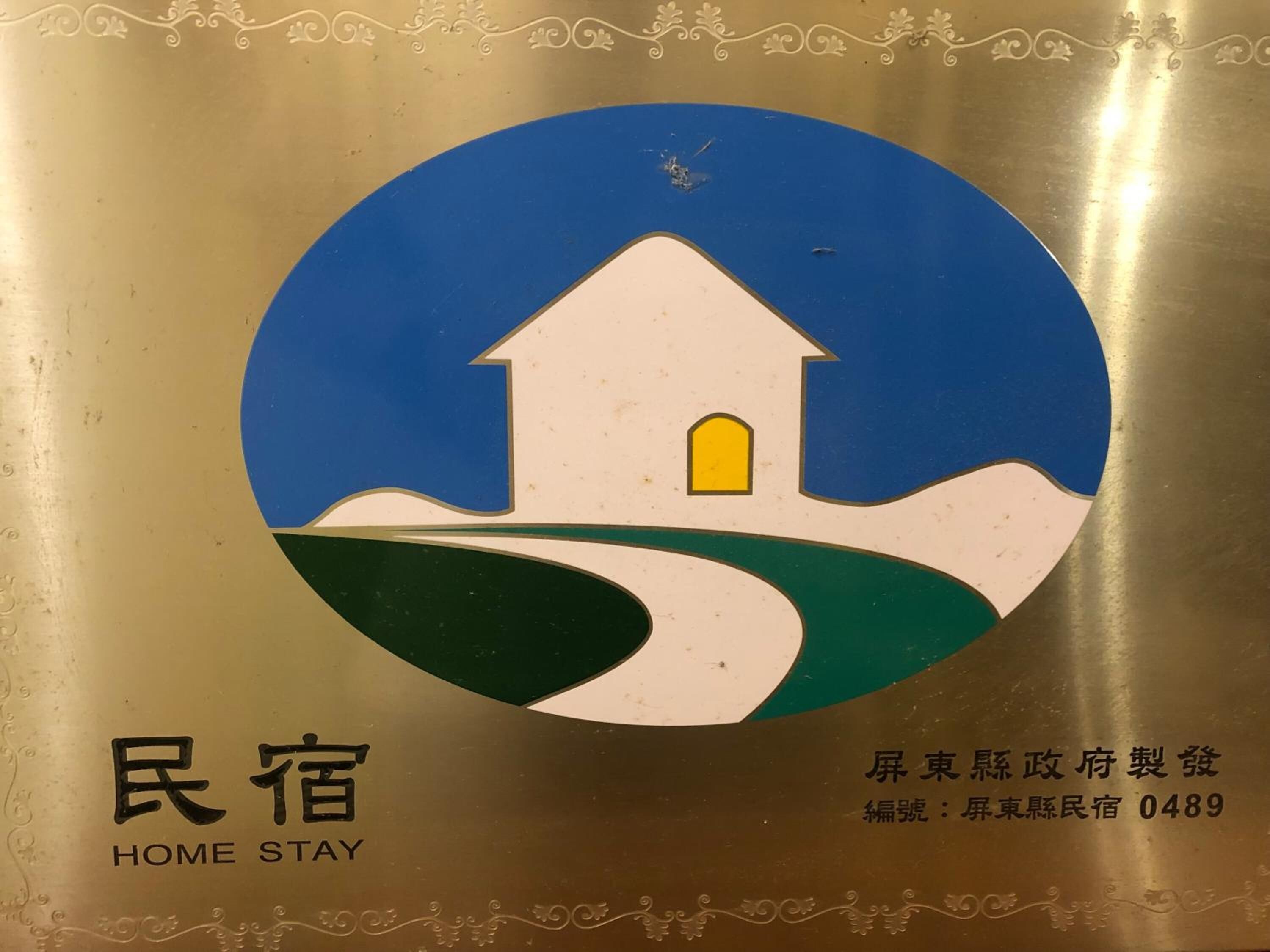 Logotipo circular com uma casa, uma estrada sinuosa e o texto 'HOME STAY'.