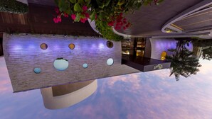 Estrutura arquitetônica moderna com superfície refletora, janelas circulares e plantas penduradas.