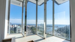 Apartamento moderno em prédio alto, com amplas janelas do chão ao teto e vista para a cidade.