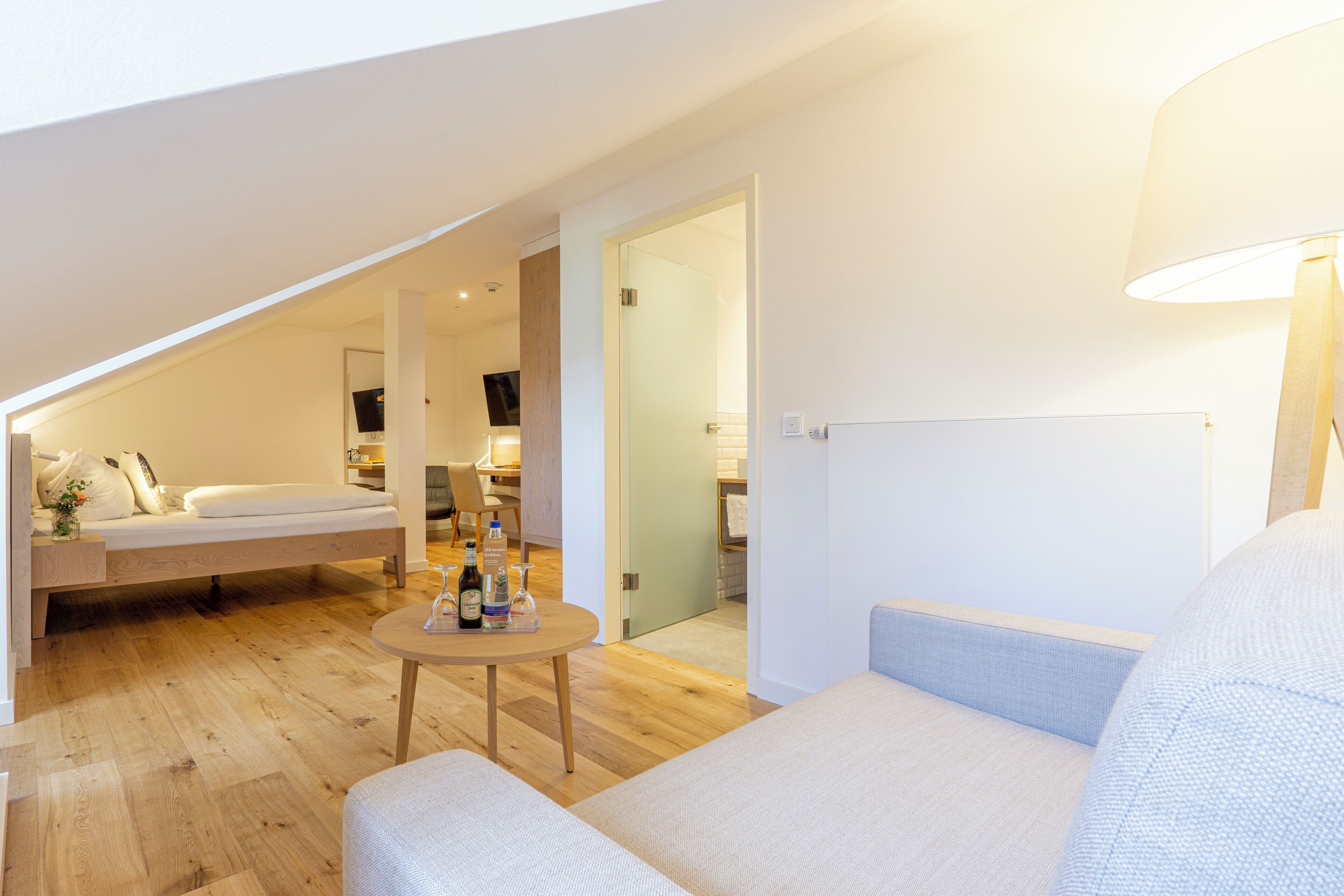 Quarto moderno estilo loft com cama beliche, uma mesinha com garrafas e um sofá.