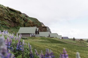 Um edifício com telhado verde e uma grande formação rochosa ao fundo.
