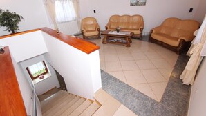 Uma sala de estar com escada de madeira, dois sofás de couro, uma mesa de centro e um quadro na parede.