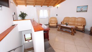 Uma sala de estar com teto de madeira, um sofá, uma mesa de centro e uma TV fixada na parede.