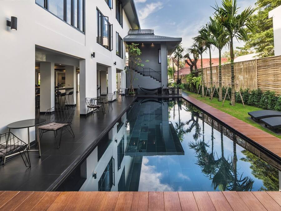 Uma área de piscina moderna ao ar livre, com barreira de vidro, assentos e escadaria para um nível superior.