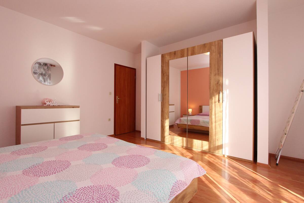 Um quarto com cama, penteadeira, espelho e guarda-roupa.