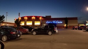Um estacionamento com vários carros estacionados em frente a um edifício com uma placa de neon que diz 'LIVIN' SKY Casino'.