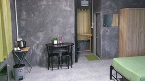 Quarto compacto com cama, uma pequena mesa com cadeiras, cozinha compacta e um guarda-roupa.