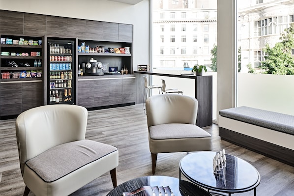 Quarto de hotel moderno com área de estar, minibar e vista para a cidade.