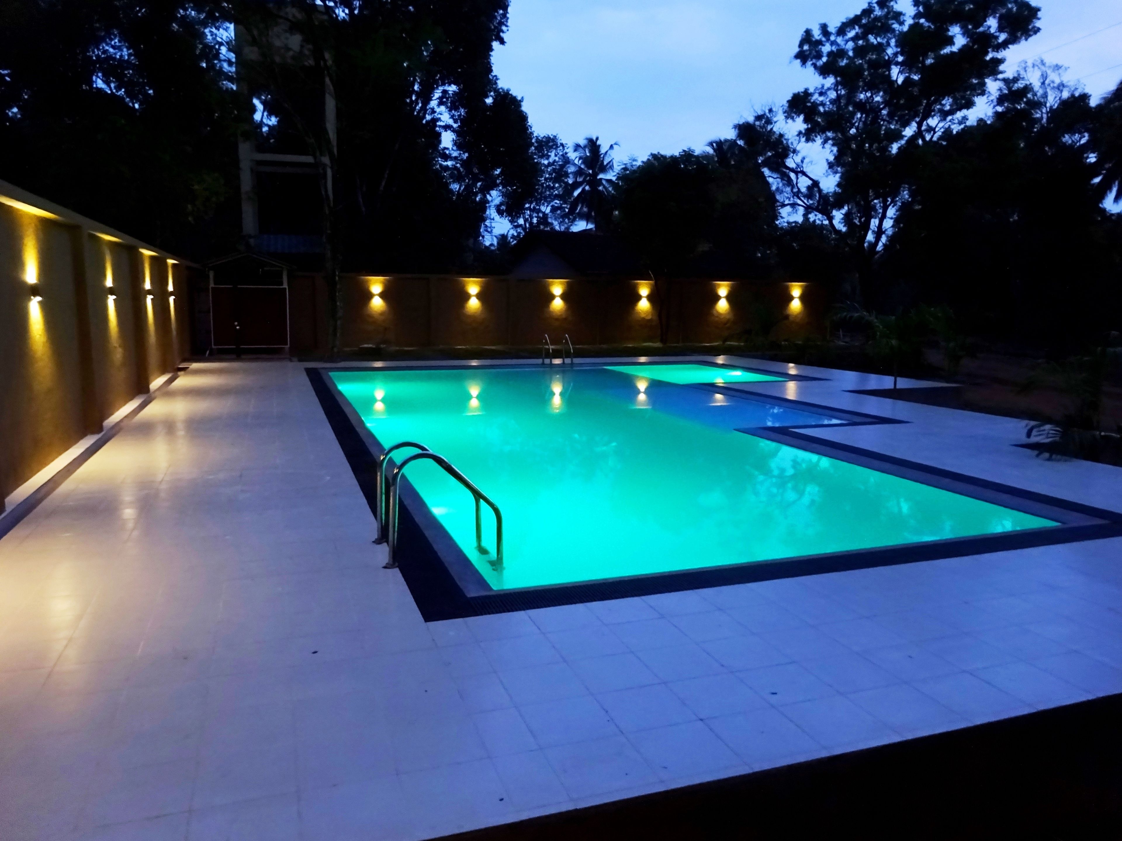 Piscina com deck ladrilhado e escada de metal.