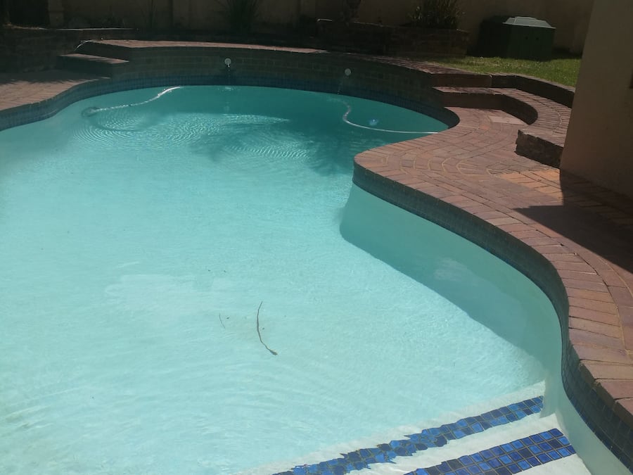 Piscina com água azul cristalina e borda revestida.