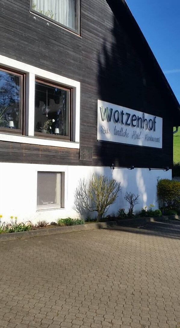 Um edifício moderno com uma placa indicando 'Watzenhof Gasthof Hotel-restaurant'.