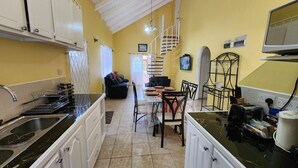 Uma cozinha compacta com área de refeições, uma escada e uma sala de estar.
