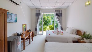 Quarto de hotel com duas camas, uma escrivaninha, um frigorífico e uma janela grande com cortinas.