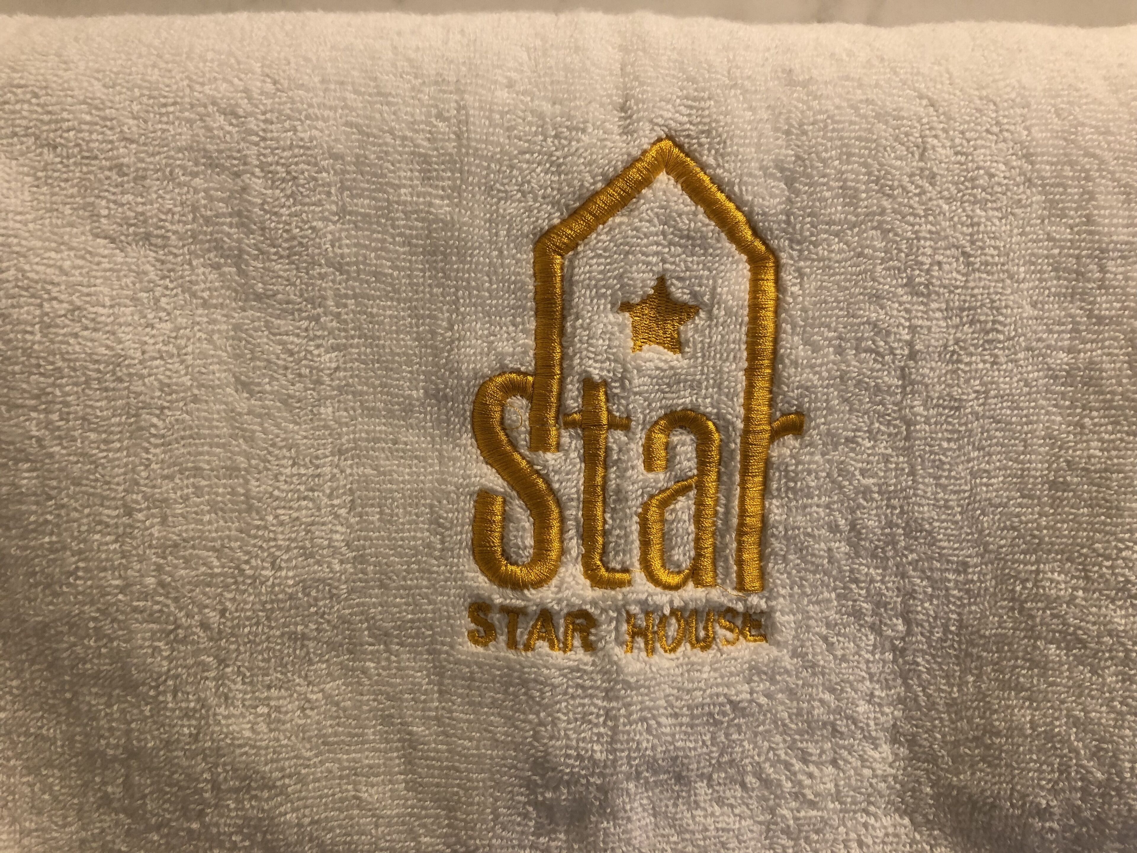 Uma toalha com bordado dourado ostentando a inscrição 'Star House'.