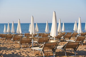 Praia particular, areia branca, espreguiçadeiras, guarda-sóis 