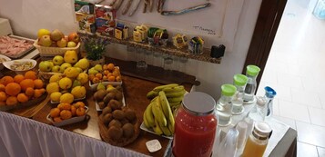 Mesa de buffet com diversas frutas, legumes e acompanhamentos.