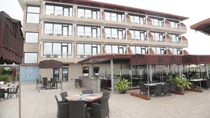 Um hotel com vários andares, áreas de refeições ao ar livre, um bar e uma piscina.