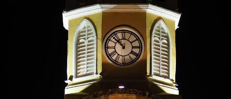 Um campanário com um grande mostrador de relógio iluminado e duas janelas em arco.