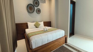 Quarto moderno com cama de madeira, roupa de cama branca, arte decorativa na parede e vista para o corredor.