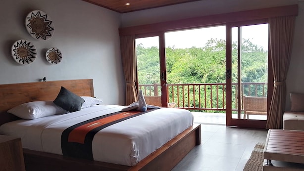 Quarto com uma cama grande, cabeceira de madeira e vista para uma varanda com guarda-corpo.