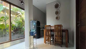 Uma área de refeições com mesa, cadeiras, um bebedouro e arte decorativa na parede.