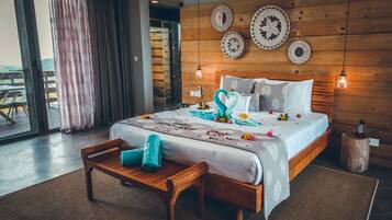 Quarto de hotel com uma cama grande, cabeceira de madeira e um banco de madeira com toalhas.