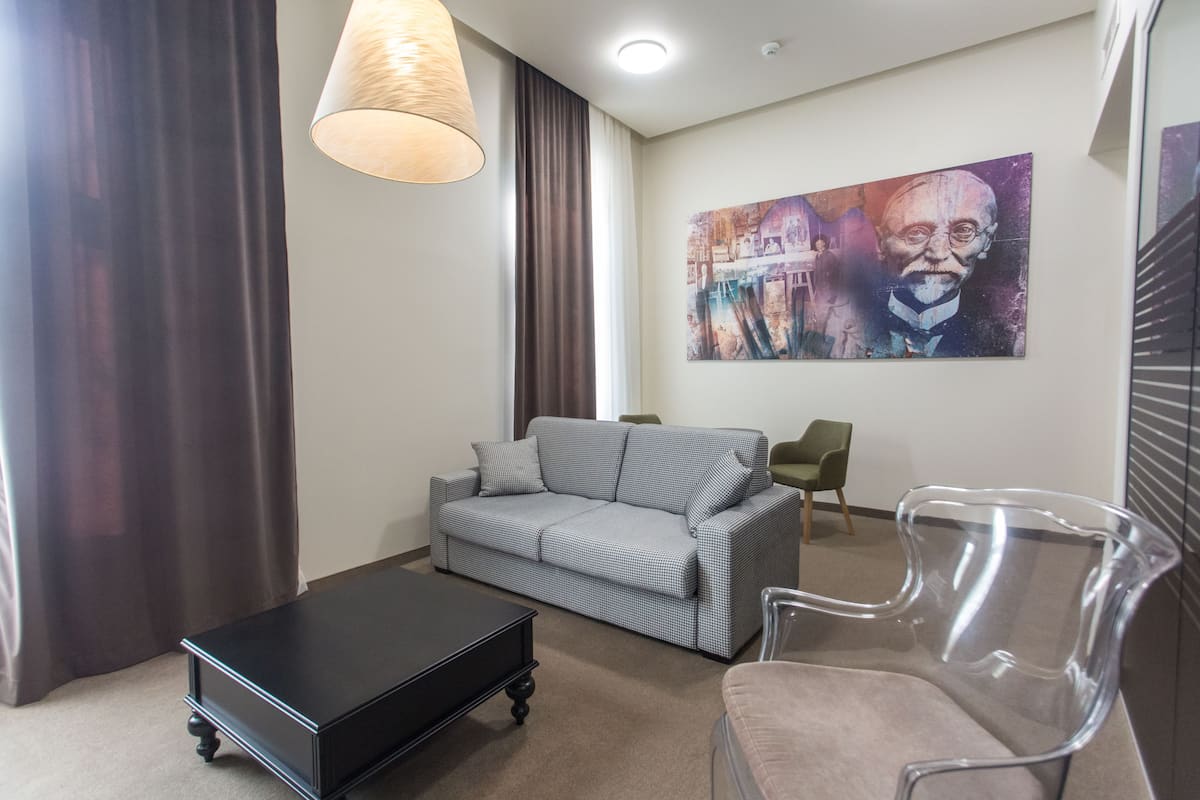 Uma sala de estar moderna com um sofá, uma mesa de centro, uma cadeira transparente e um quadro na parede.