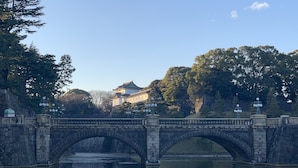 Uma ponte de pedra sobre águas calmas, com um edifício tradicional ao fundo.