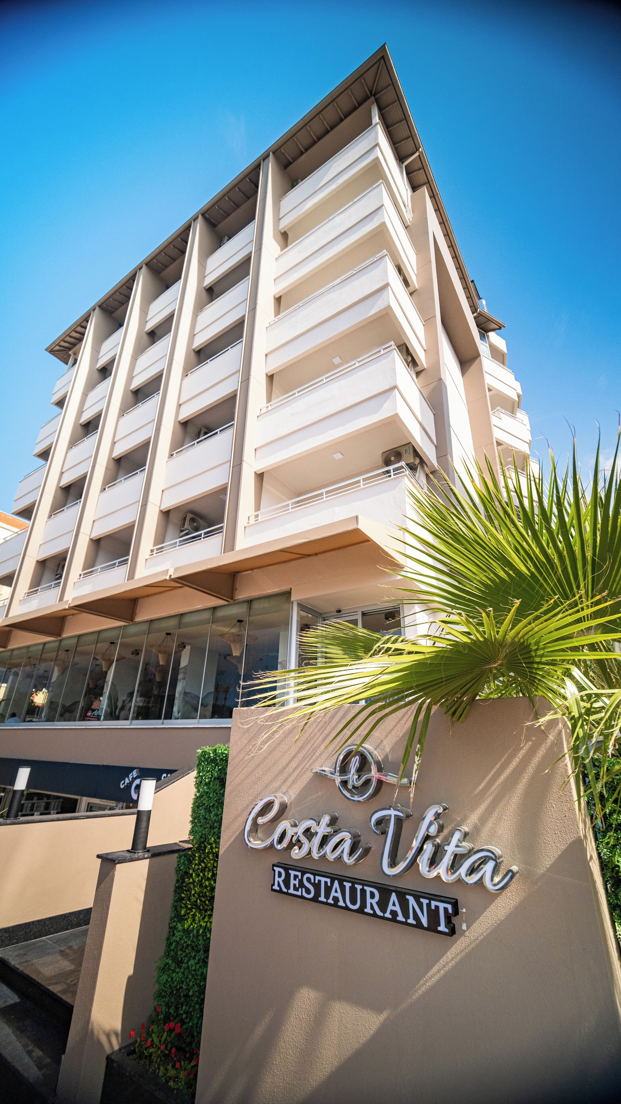 Um edifício de vários andares com um letreiro para o Restaurante Costa Vita.