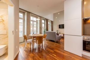 Uma cozinha moderna com forno embutido, área de jantar com mesa redonda e cadeiras, e janelas grandes com cortinas.